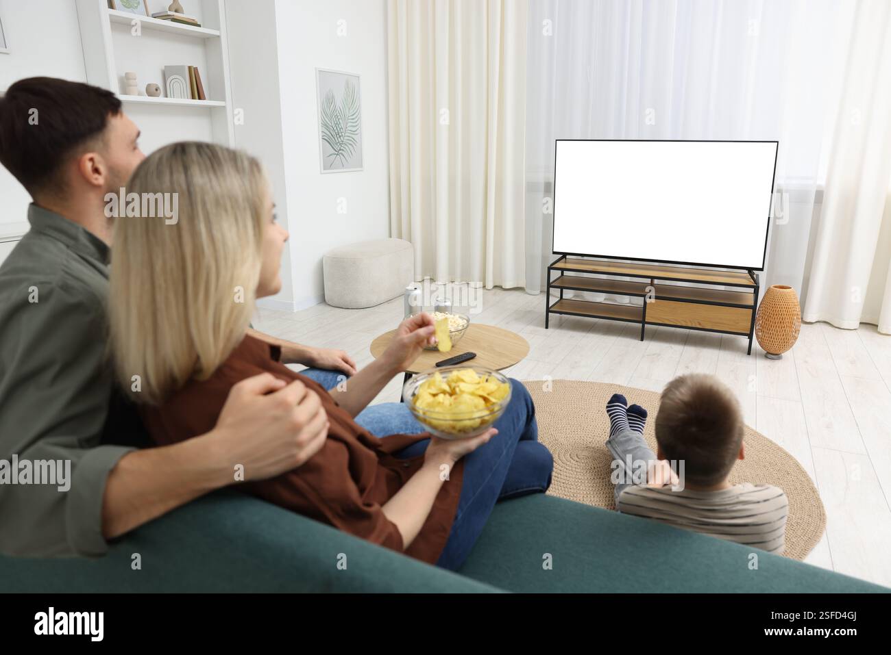 Happy family with snacks and drinks watching tv together at home Stock ...