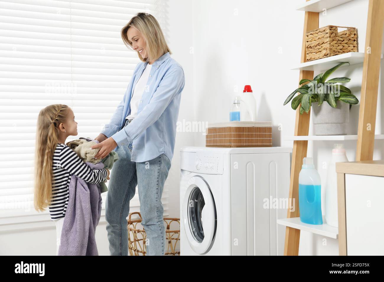 Little girl helping her mom doing laundry at home Stock Photo - Alamy