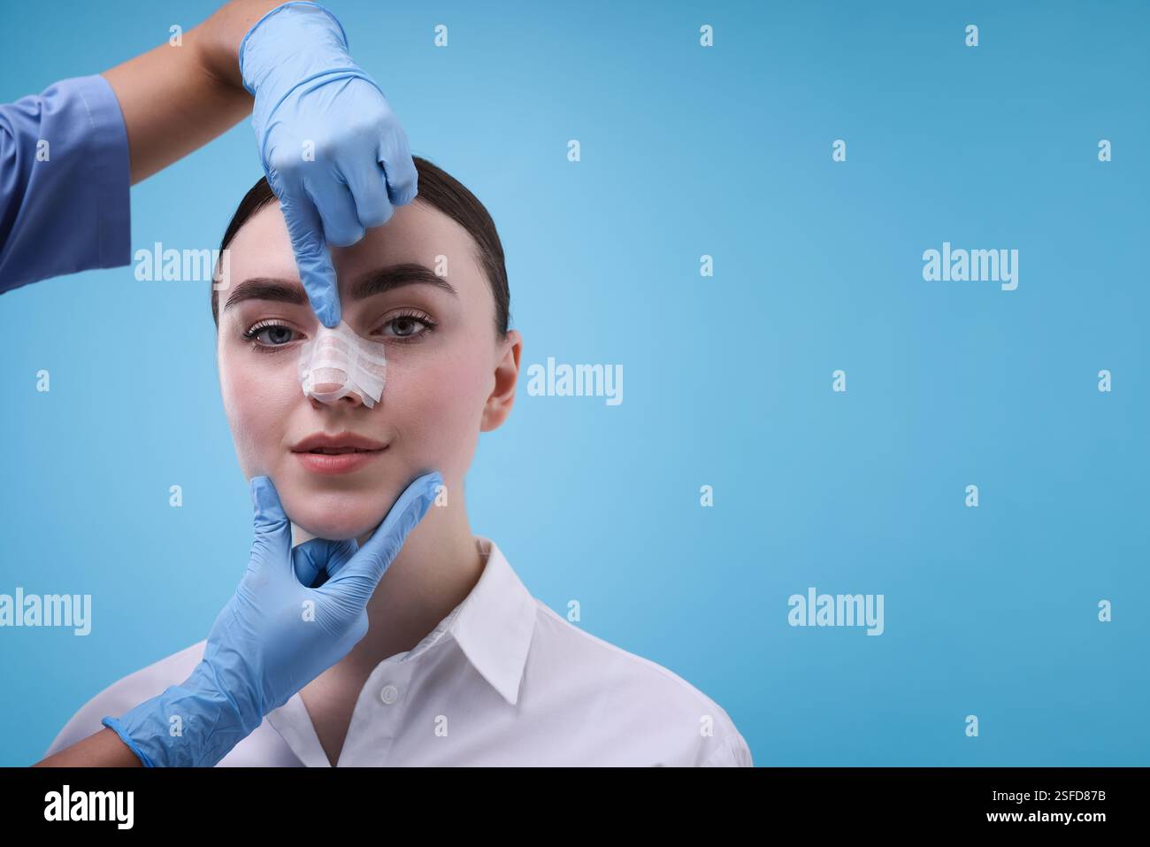 Doctor checking patient's nose after plastic surgery operation on light ...