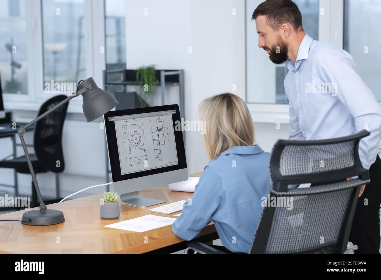 Technicians making digital engineering drawing on computer at desk in ...