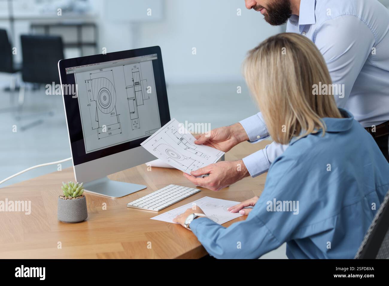 Technician making digital engineering drawing on computer at desk in ...