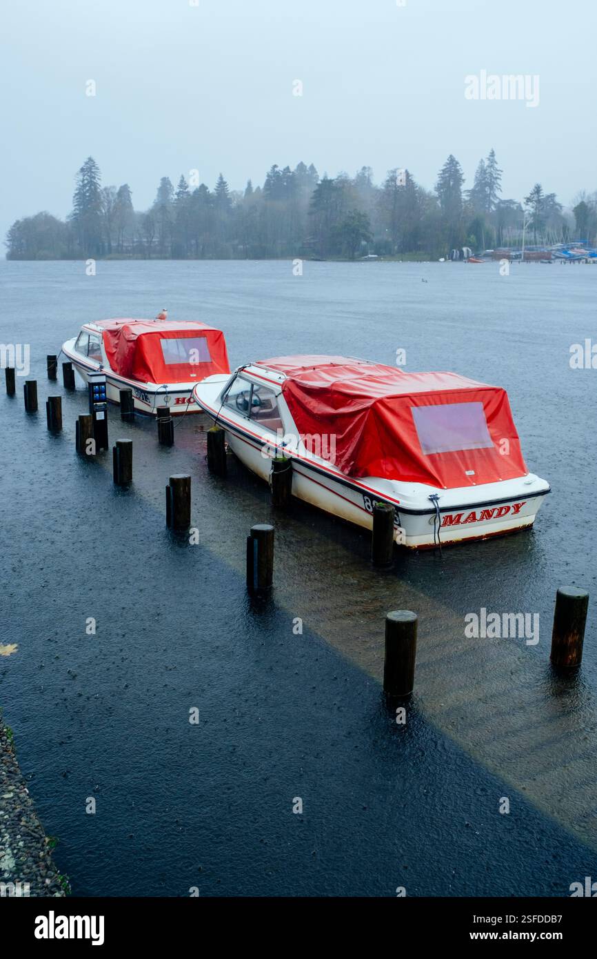flooded boat walkways and red & white hire boats on a rainy day at lake ...