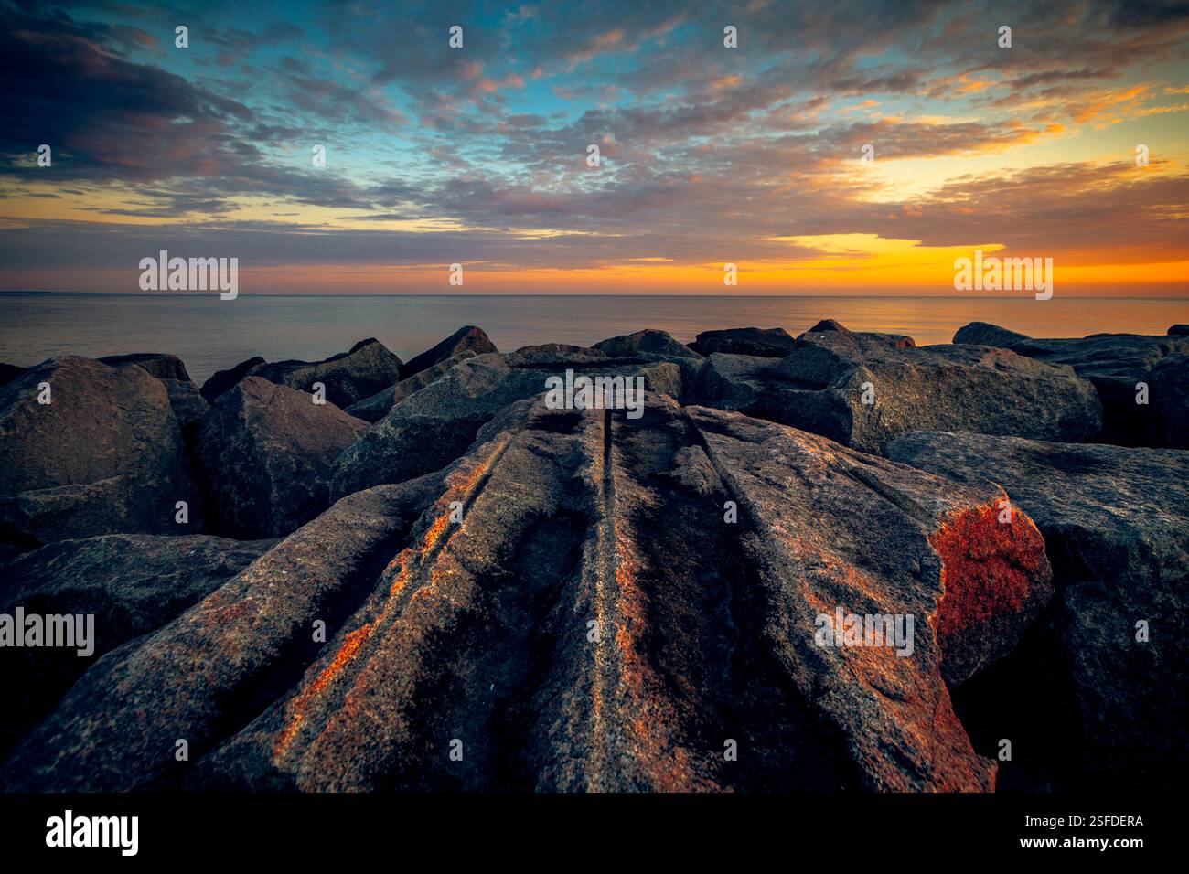 Close-up of a coastal rock wavebreaker along the Baltic Sea at sunset ...