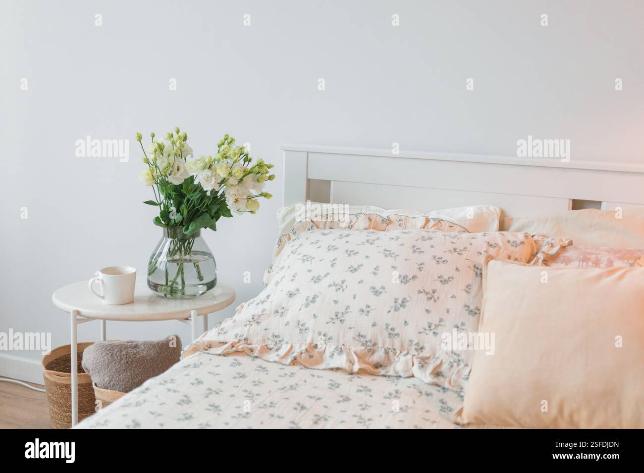 Bedroom interior with a bunch of flowers on a bedside table and baskets ...