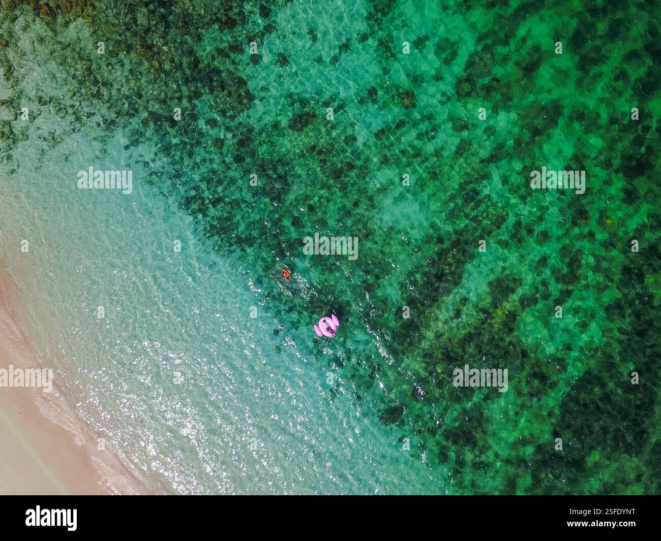 Distant aerial view of two people floating on inflatable pool floats in ...