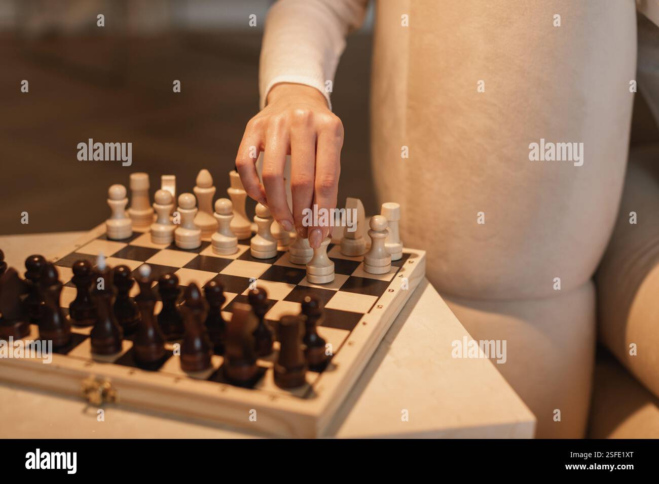 Close-up of a woman sitting in a living room playing a game of chess ...