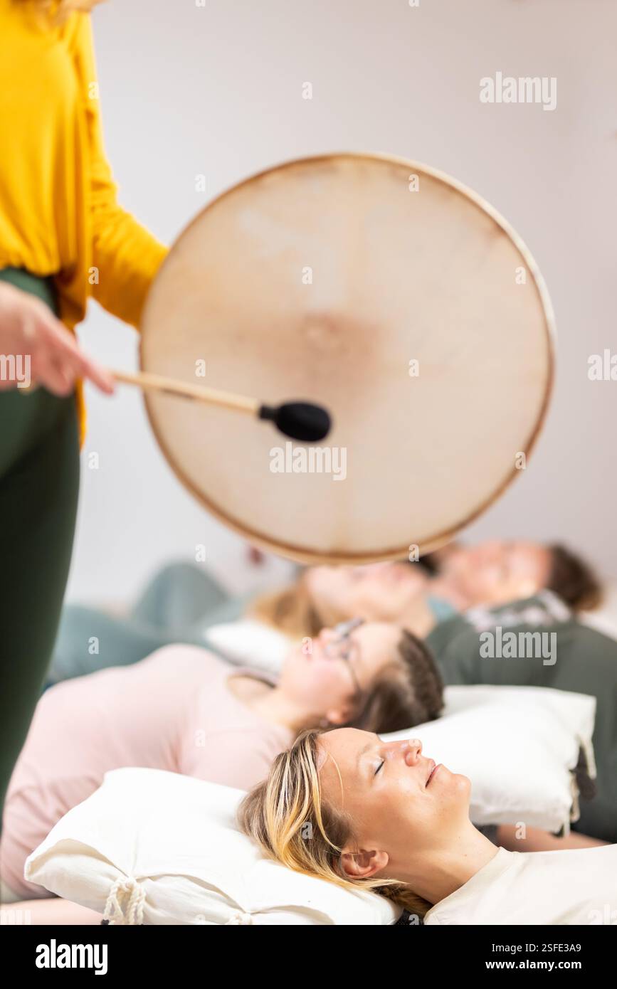 Group therapy session with Tibetan drum for group of women lying on ...