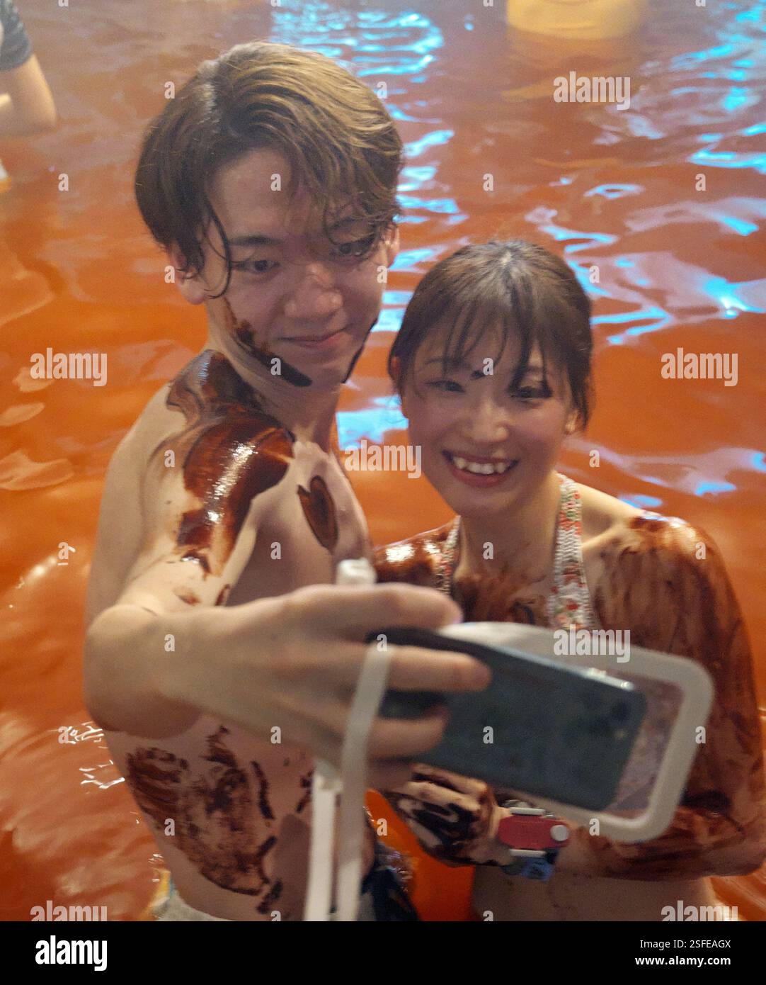 Hakone, Japan. 09th Feb, 2025. Bathers take a selfie in the chocolate ...
