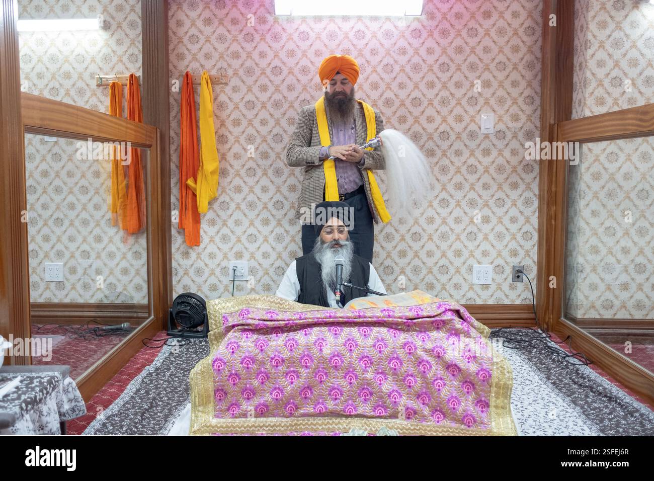A Sikh man holds his Chaur Sahib fly whisk at an Akhand Path service ...