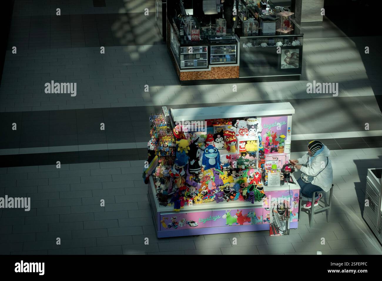 A female vendor bundled up & selling toys from a stand in the aisles at ...