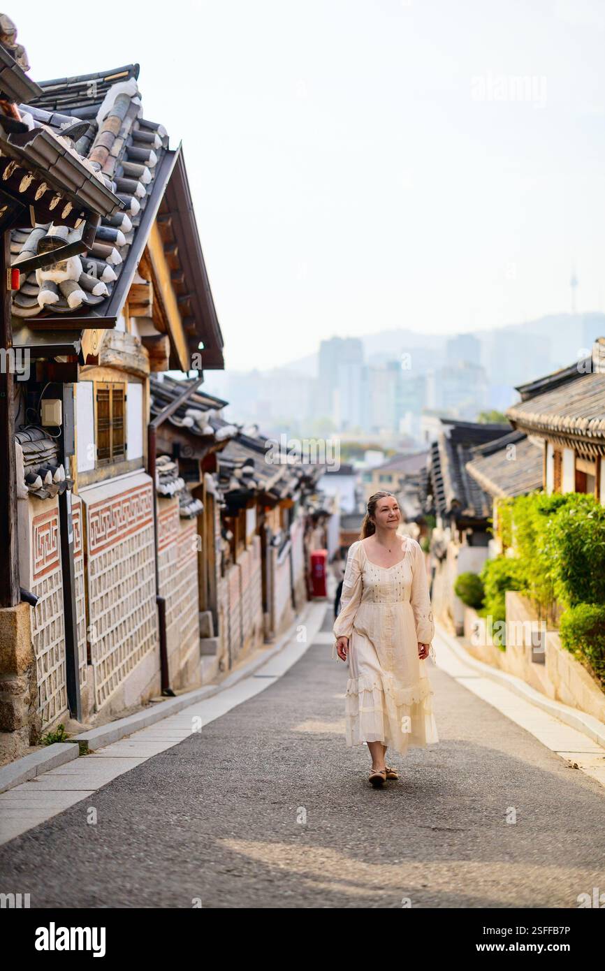 Woman walking through Bukchon Hanok Village, featuring traditional ...