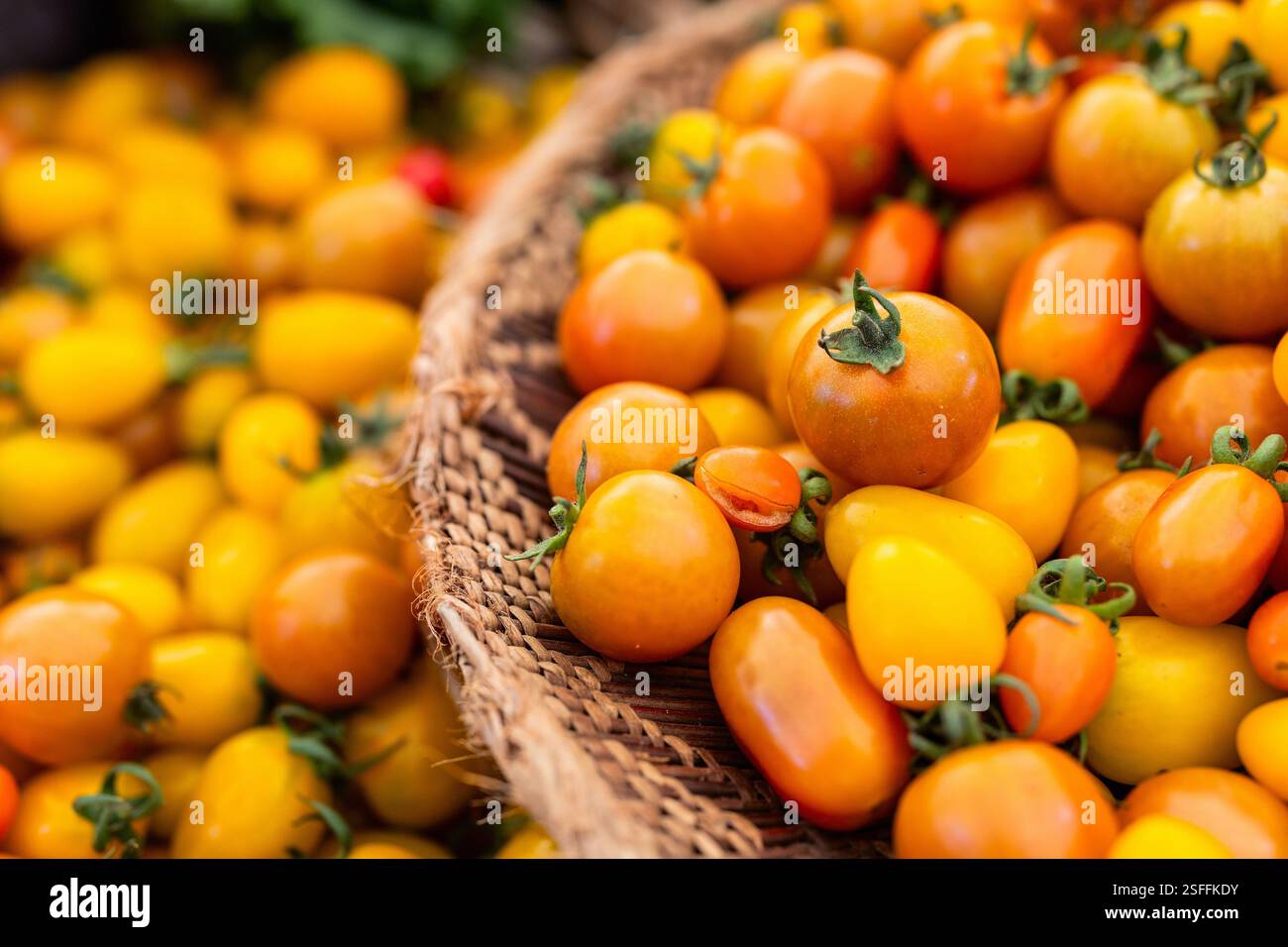 A close-up of vibrant orange and yellow cherry tomatoes displayed in a ...