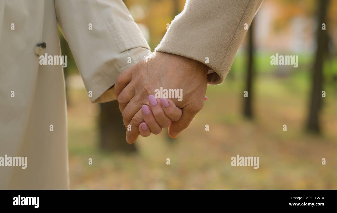 Close up holding hands couple together in park outdoors middle aged ...