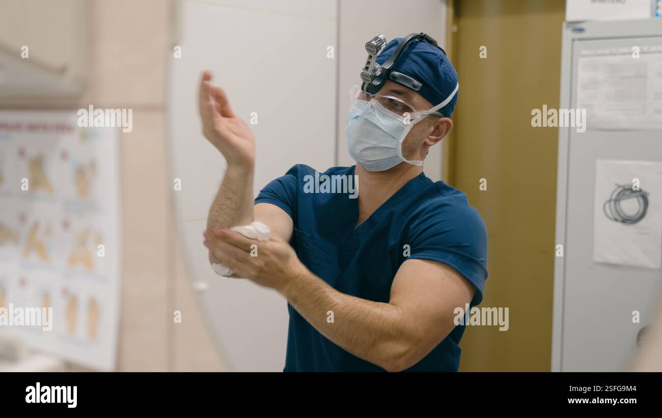 Surgeon man doctor washing hands in hospital male medic disinfect palms ...