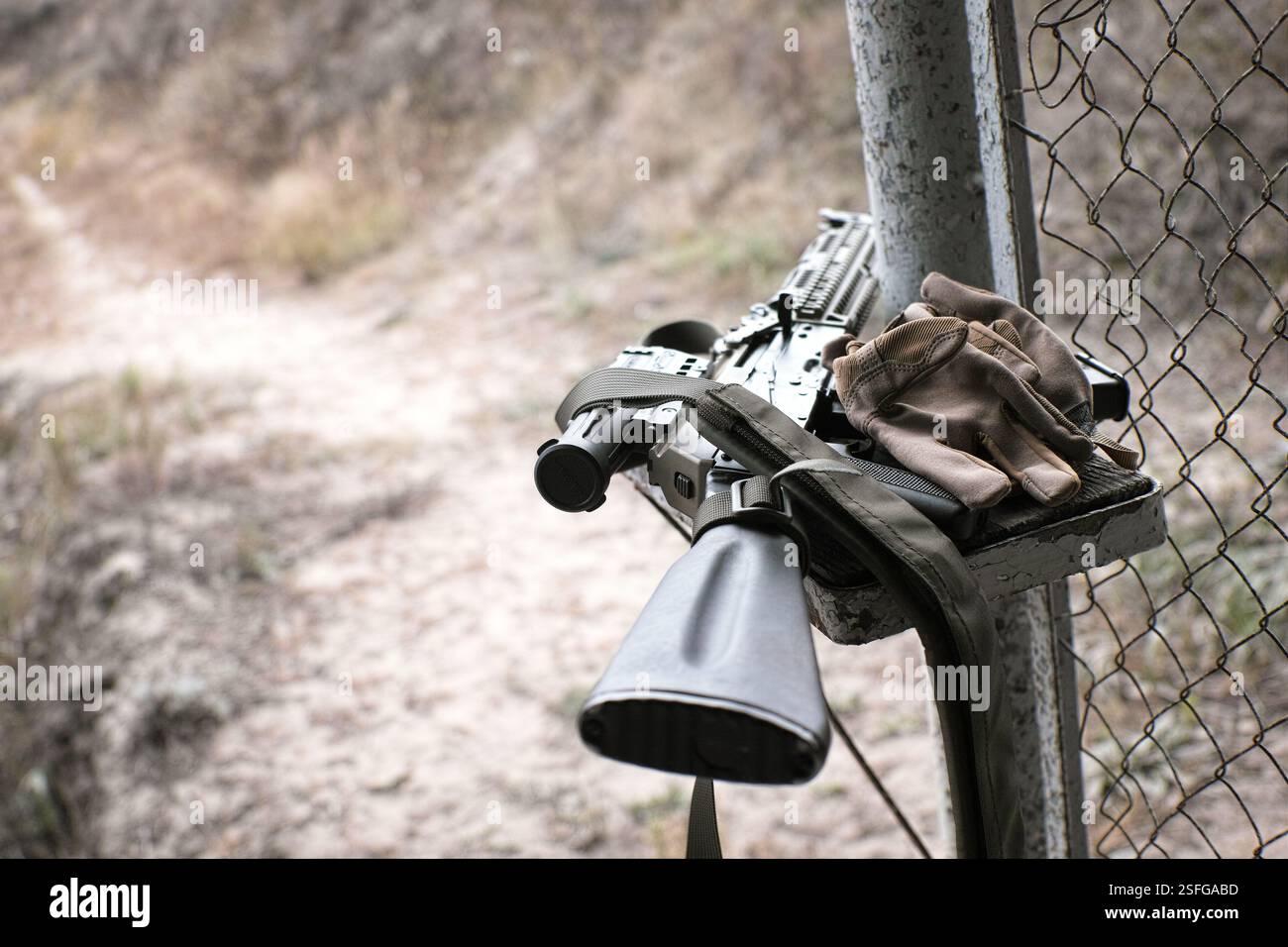an assault rifle with scope and a pair of tactical gloves at the ...