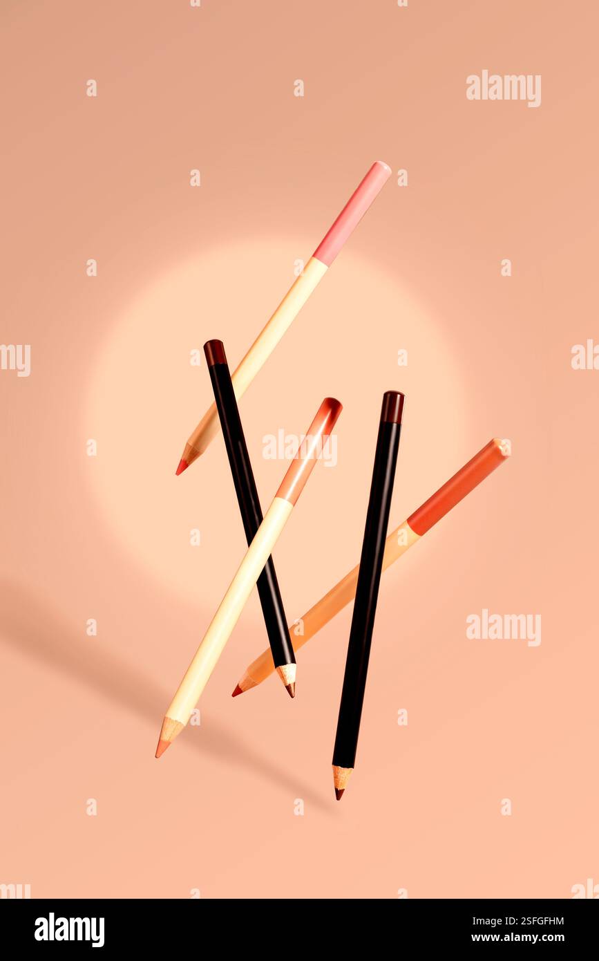 Elegant set of flying cosmetic pencils for eyes and brows in neutral tones on a soft beige ...