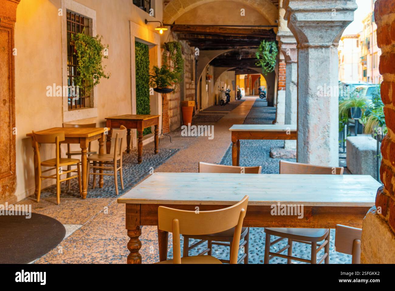 Cozy outdoor cafe with wooden tables and chairs outside under historic ...