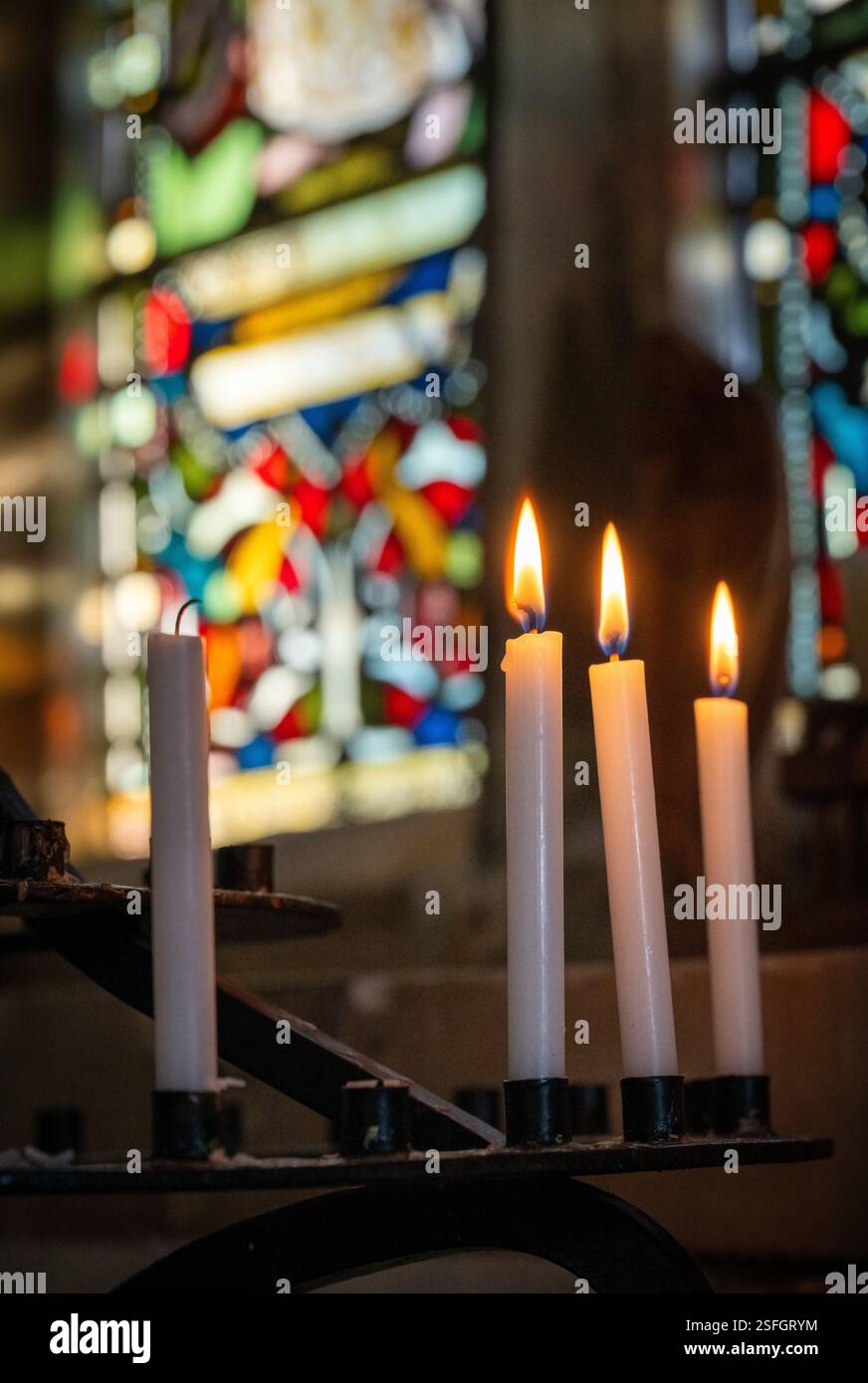 Candles in a church with stained glass window behind Stock Photo - Alamy