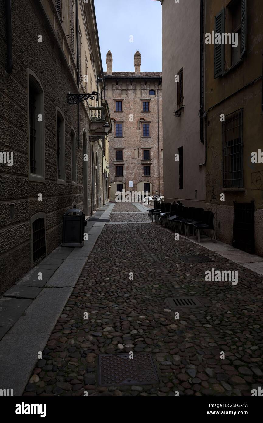 Narrow alley paved with cobblestone in the shade that leads to a square ...