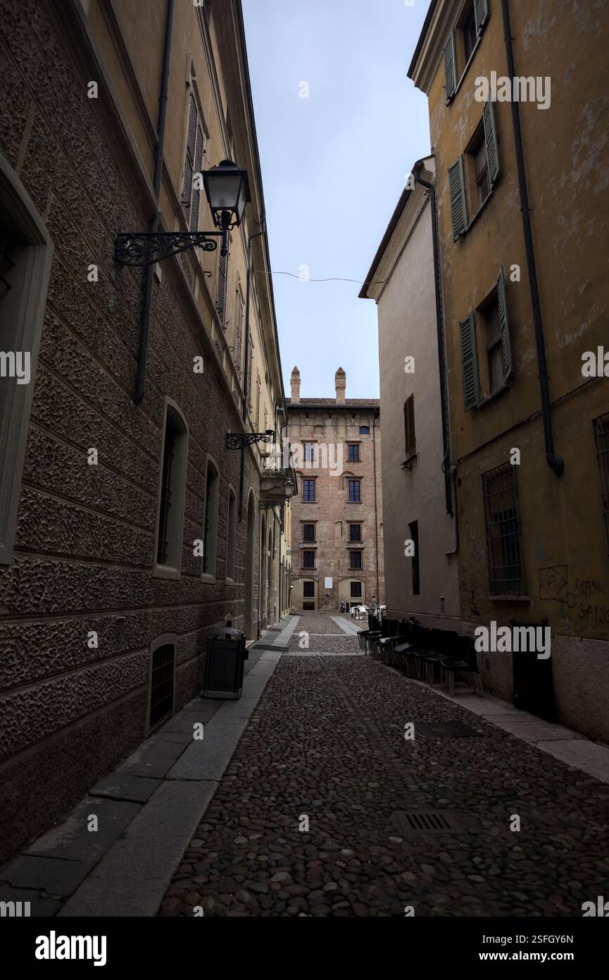 Narrow alley paved with cobblestone in the shade that leads to a square ...