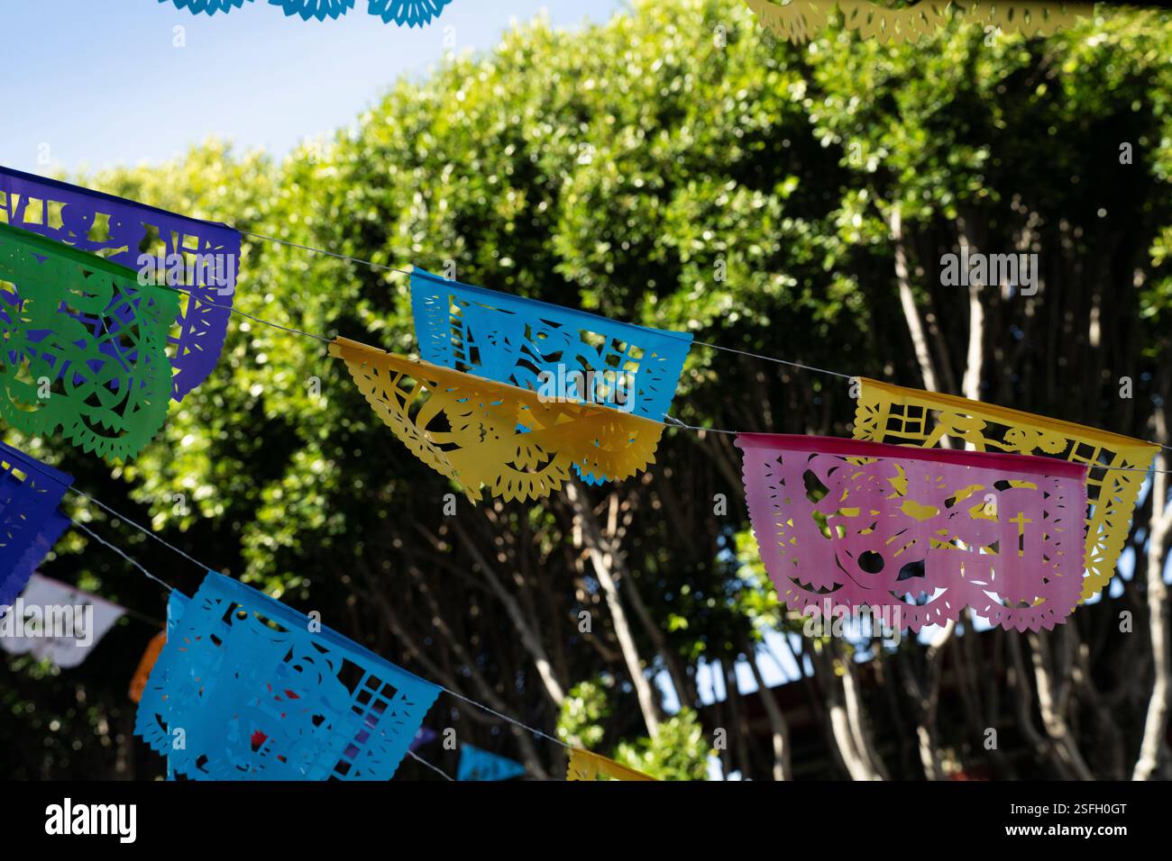 Colorful papel picado decorations hang in a Mexican town, likely ...