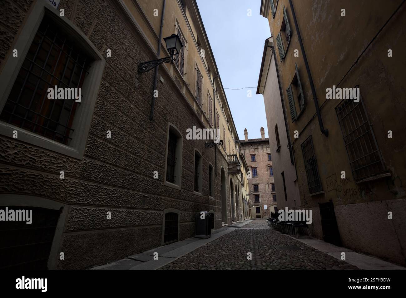 Narrow alley paved with cobblestone in the shade that leads to a square ...