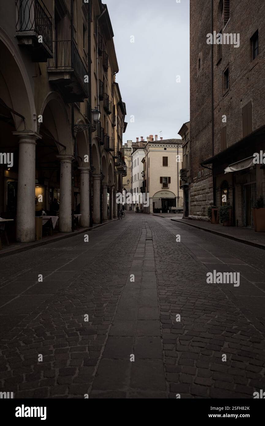 Paved street between a porchway and a historic building both with shop ...