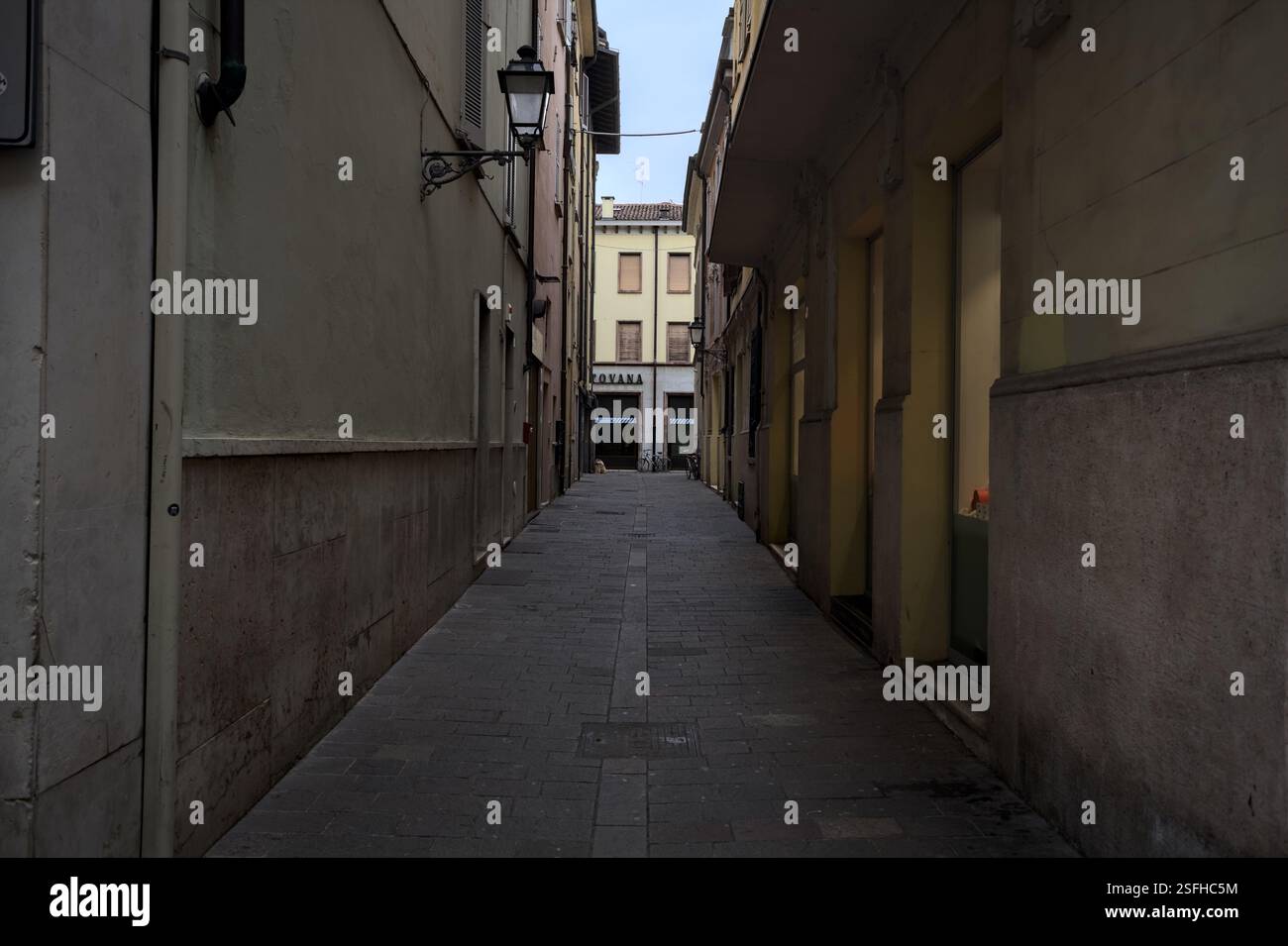 Paved alley with shop windows in the back of two buildings in an ...