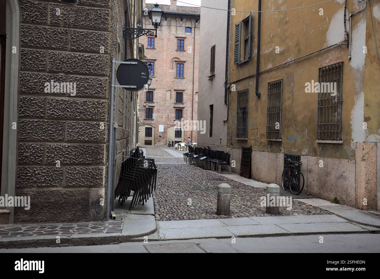 Narrow alley paved with cobblestone in the shade that leads to a square ...
