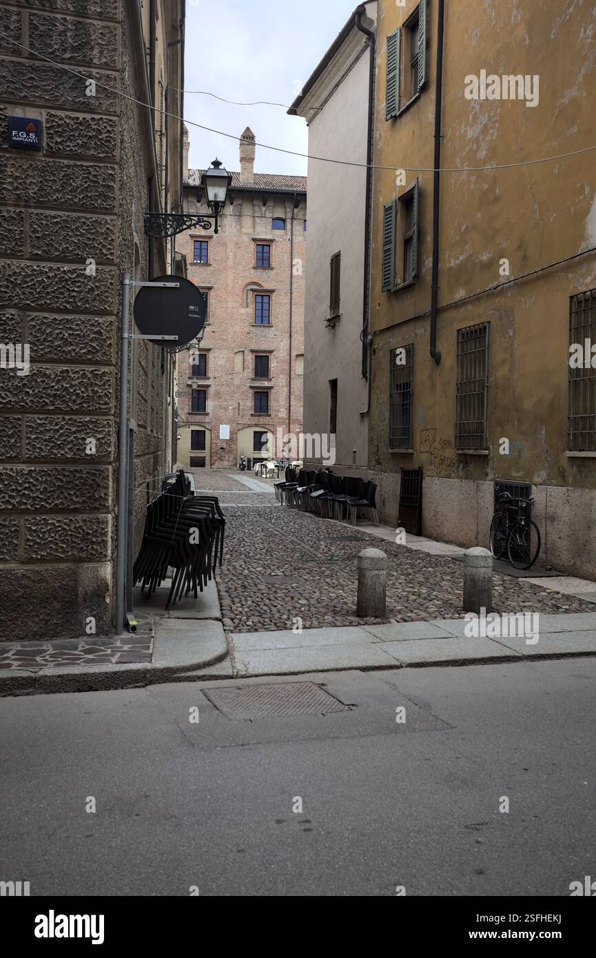 Narrow alley paved with cobblestone in the shade that leads to a square ...