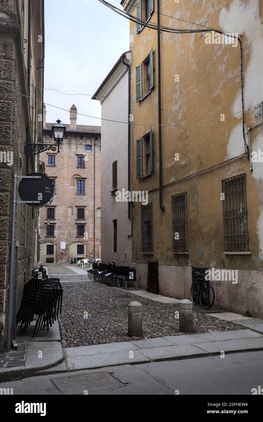 Narrow alley paved with cobblestone in the shade that leads to a square ...