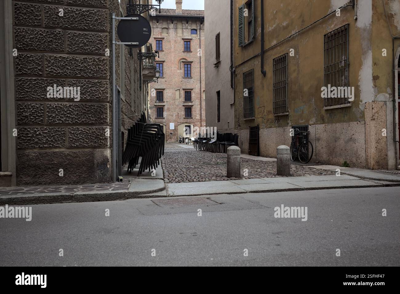 Narrow alley paved with cobblestone in the shade that leads to a square ...