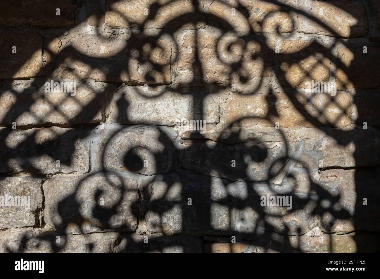 Detailed shadows of a wrought iron structure stretch across an ancient ...