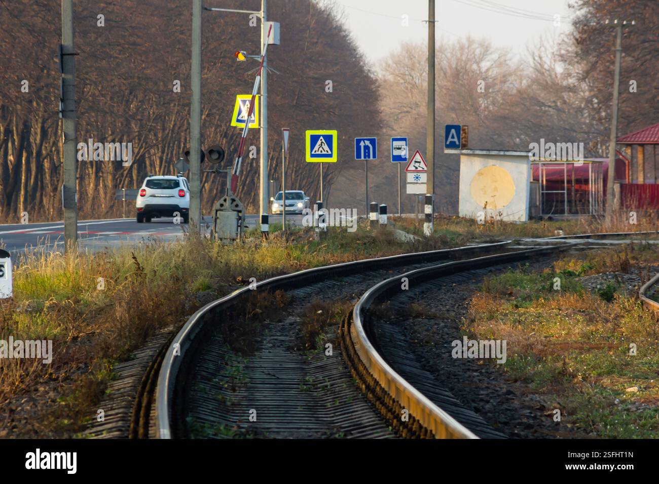 Railway tracks curve next to a road where vehicles are traveling ...
