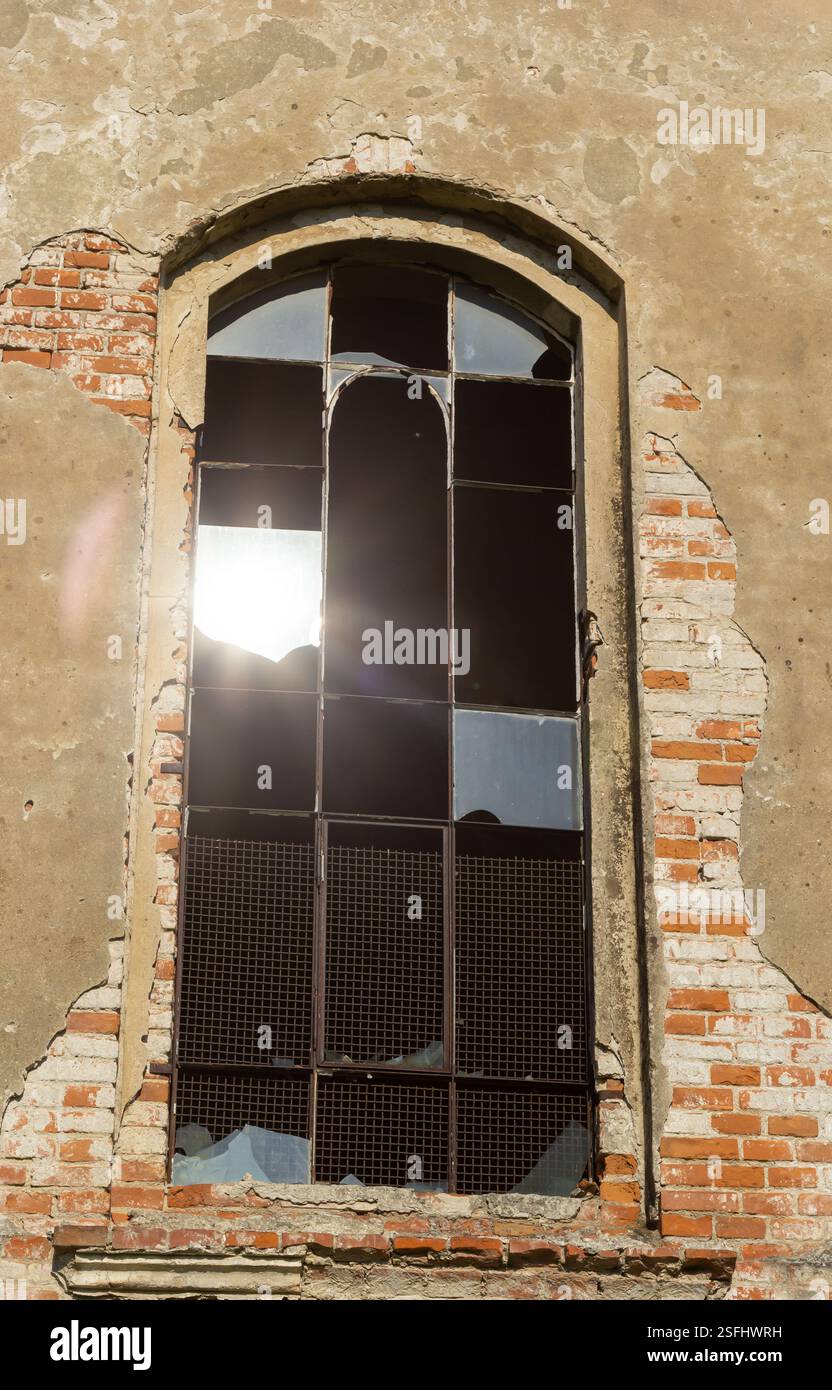 A window of an abandoned building reveals shattered glass and peeling ...
