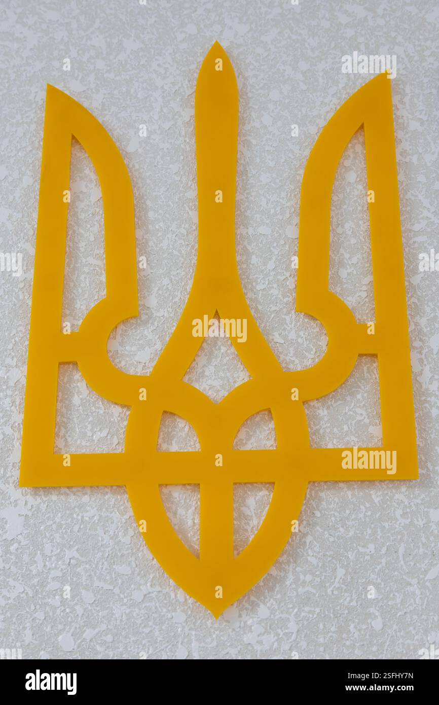 A yellow trident emblem rests on a pale textured surface, symbolizing ...