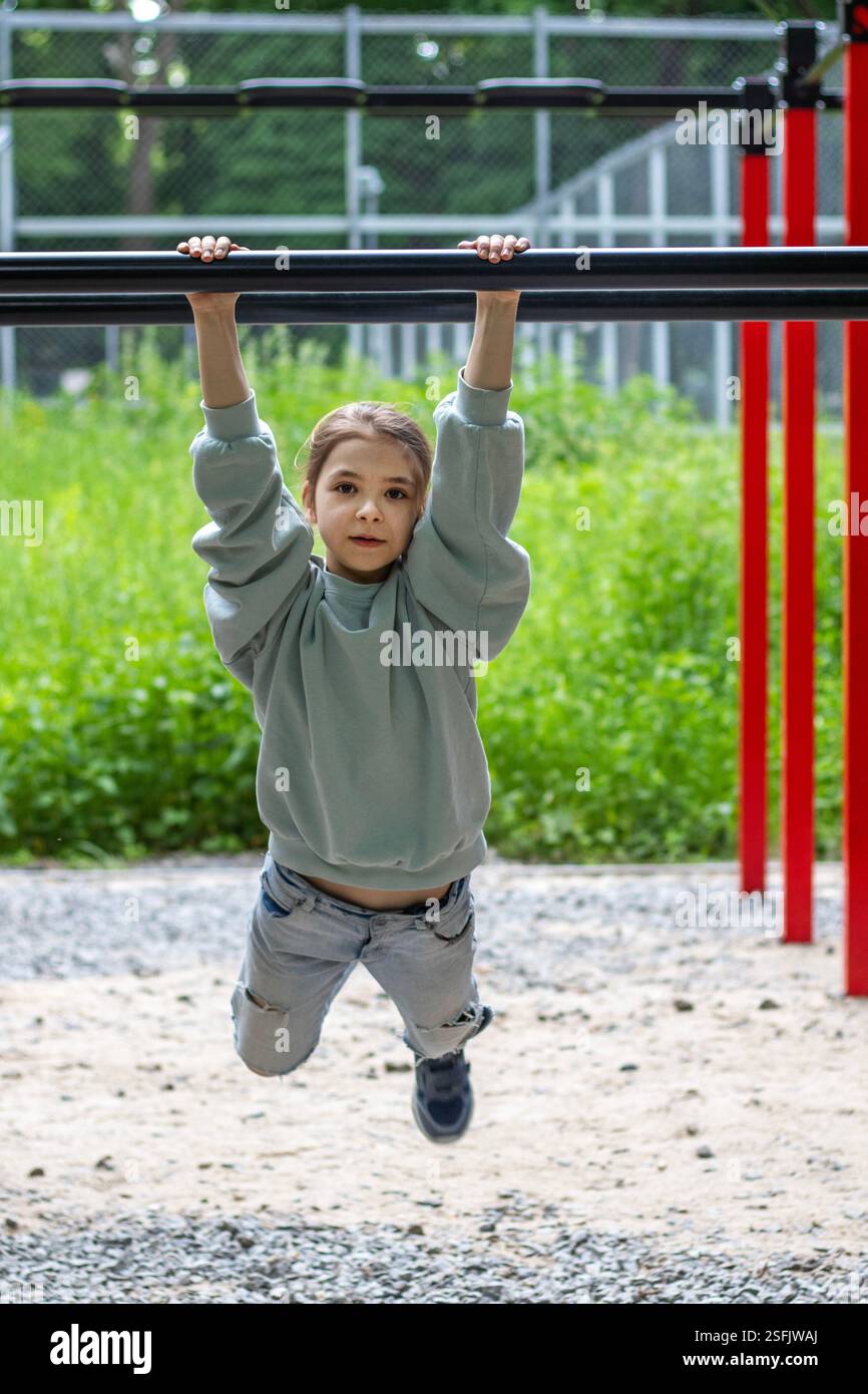 Young girl practicing on horizontal bars outdoors in recreational park ...