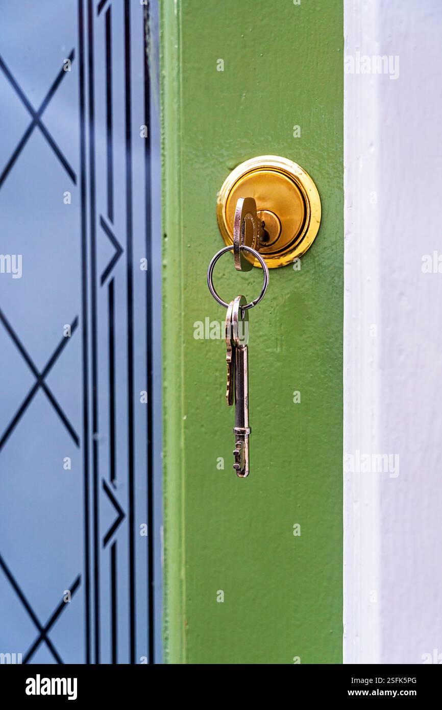 close-up of keys in the green painted wooden front door of a house with ...