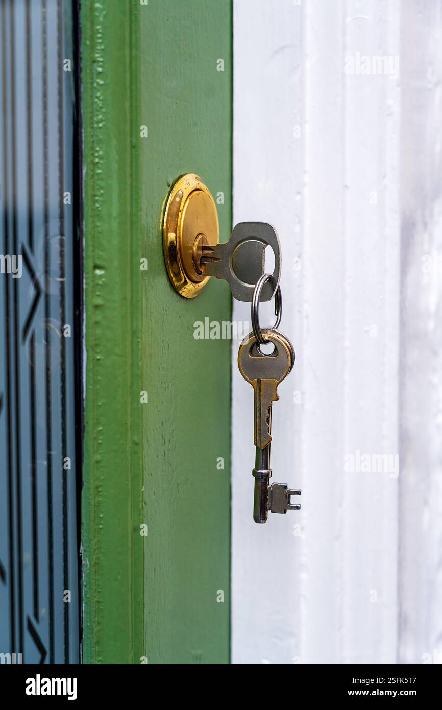 close-up of keys in the green painted wooden front door of a house with ...