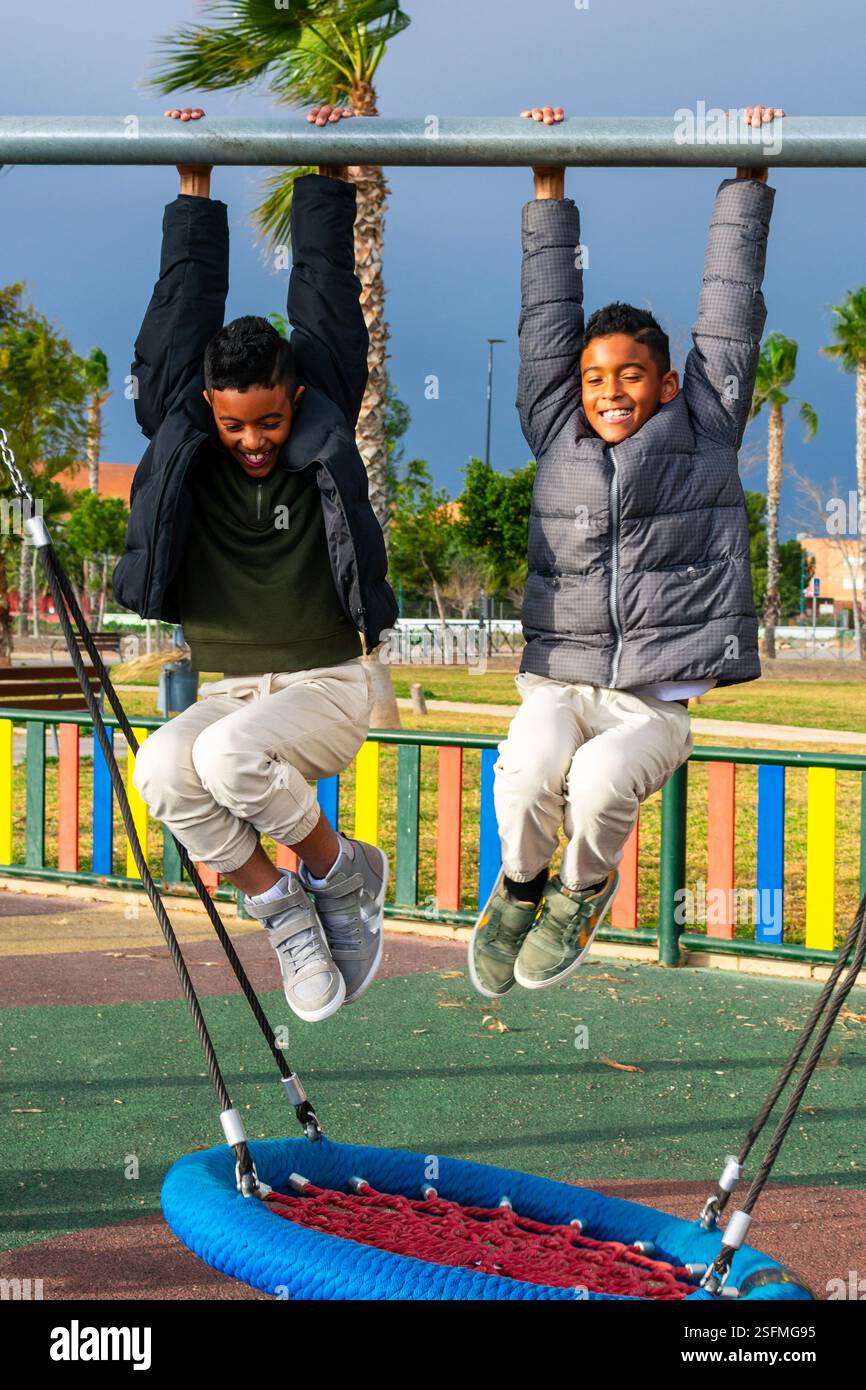 Two cheerful brothers are enjoying their time hanging from a horizontal ...