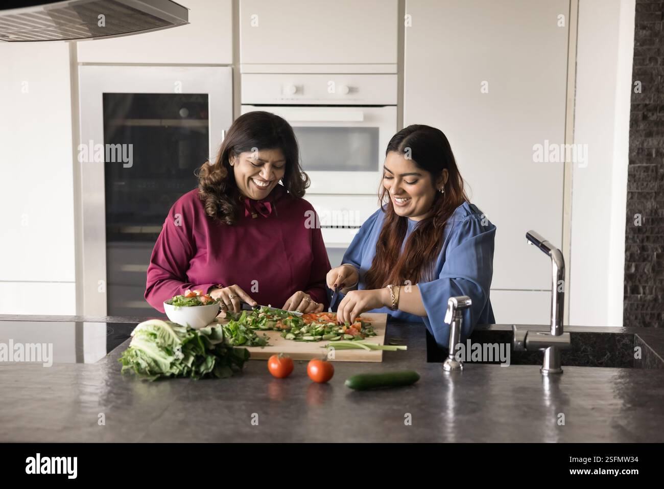 Two women preparing fresh vegetables together in modern kitchen Stock ...