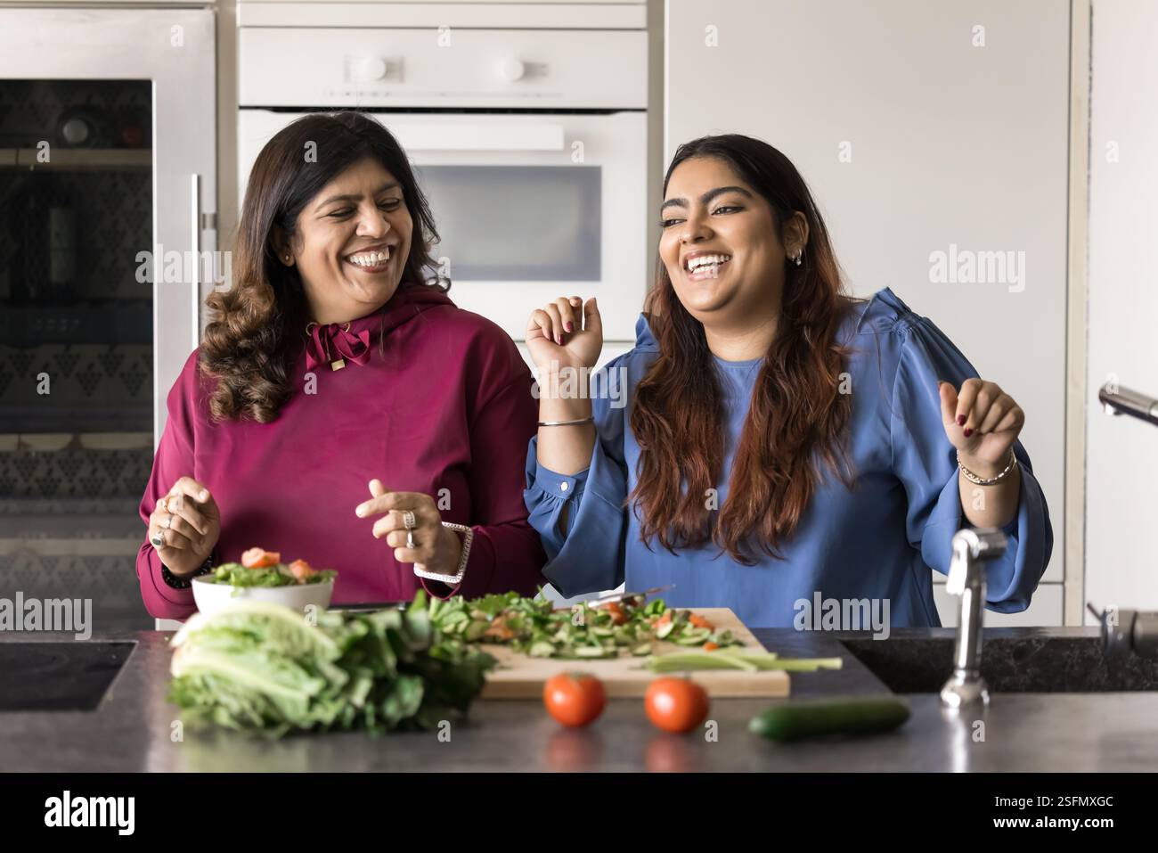 Two Indian women dancing while cooking at home Stock Photo - Alamy