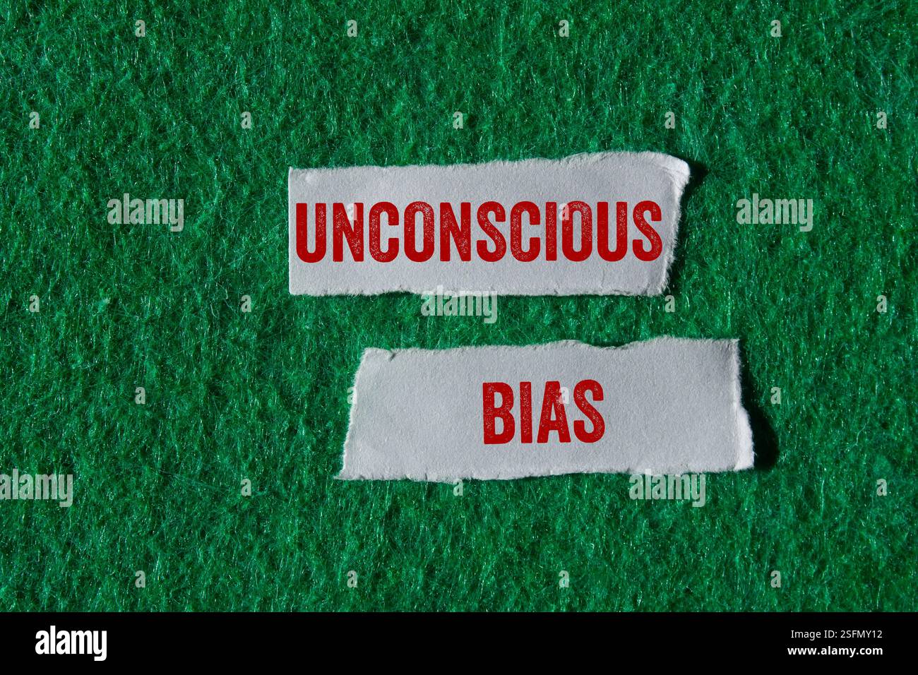 Unconscious bias message written on ripped torn paper pieces on green background. Conceptual ...