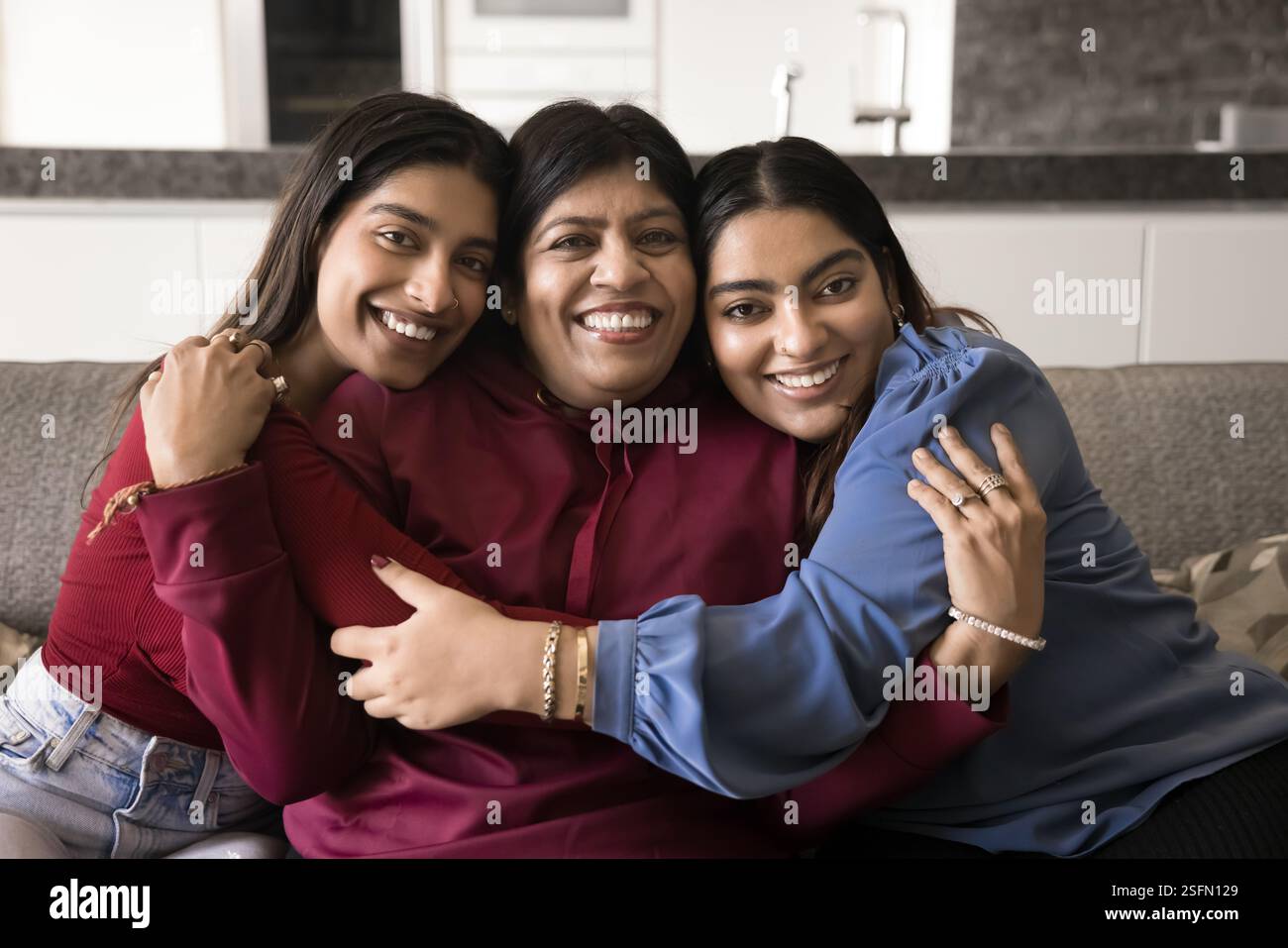 Older mother enjoys moment of tender hugs with grownup daughters Stock ...