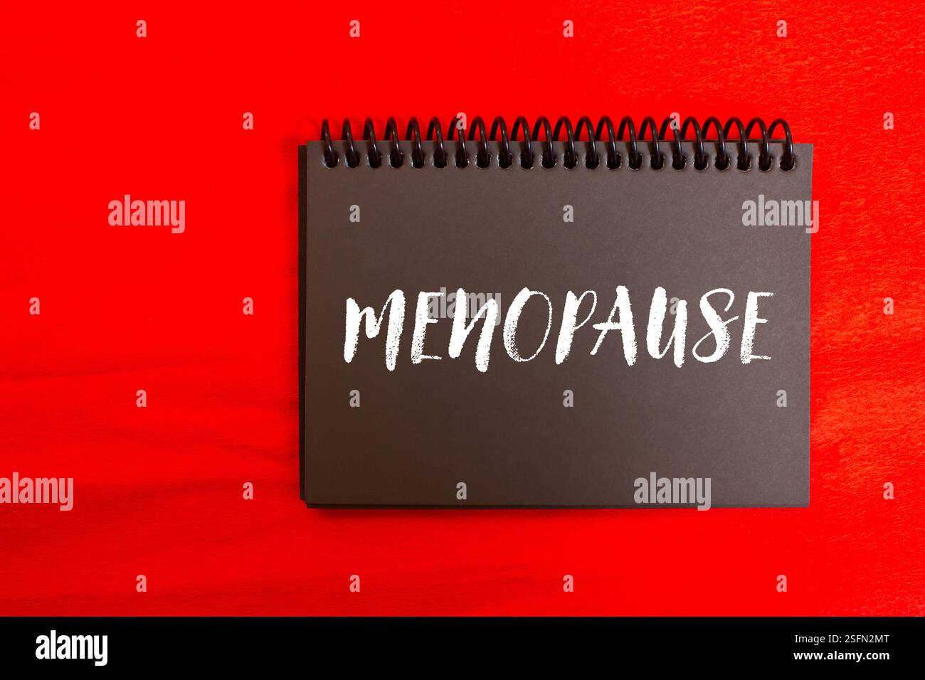 Menopause message written on black notebook page on red background ...