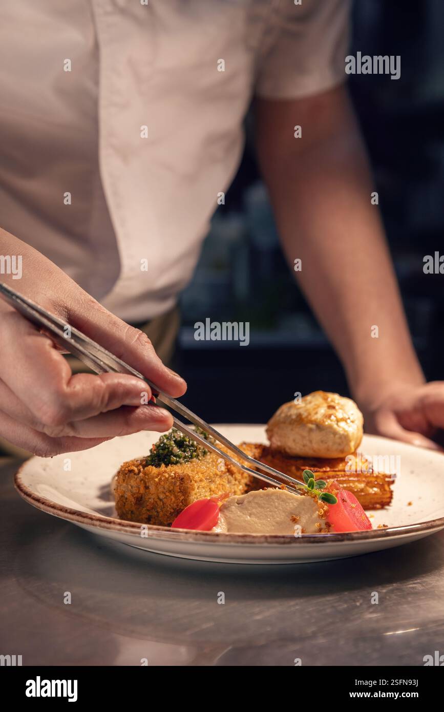 Professional chef adding finishing touches to a plated gourmet meal ...