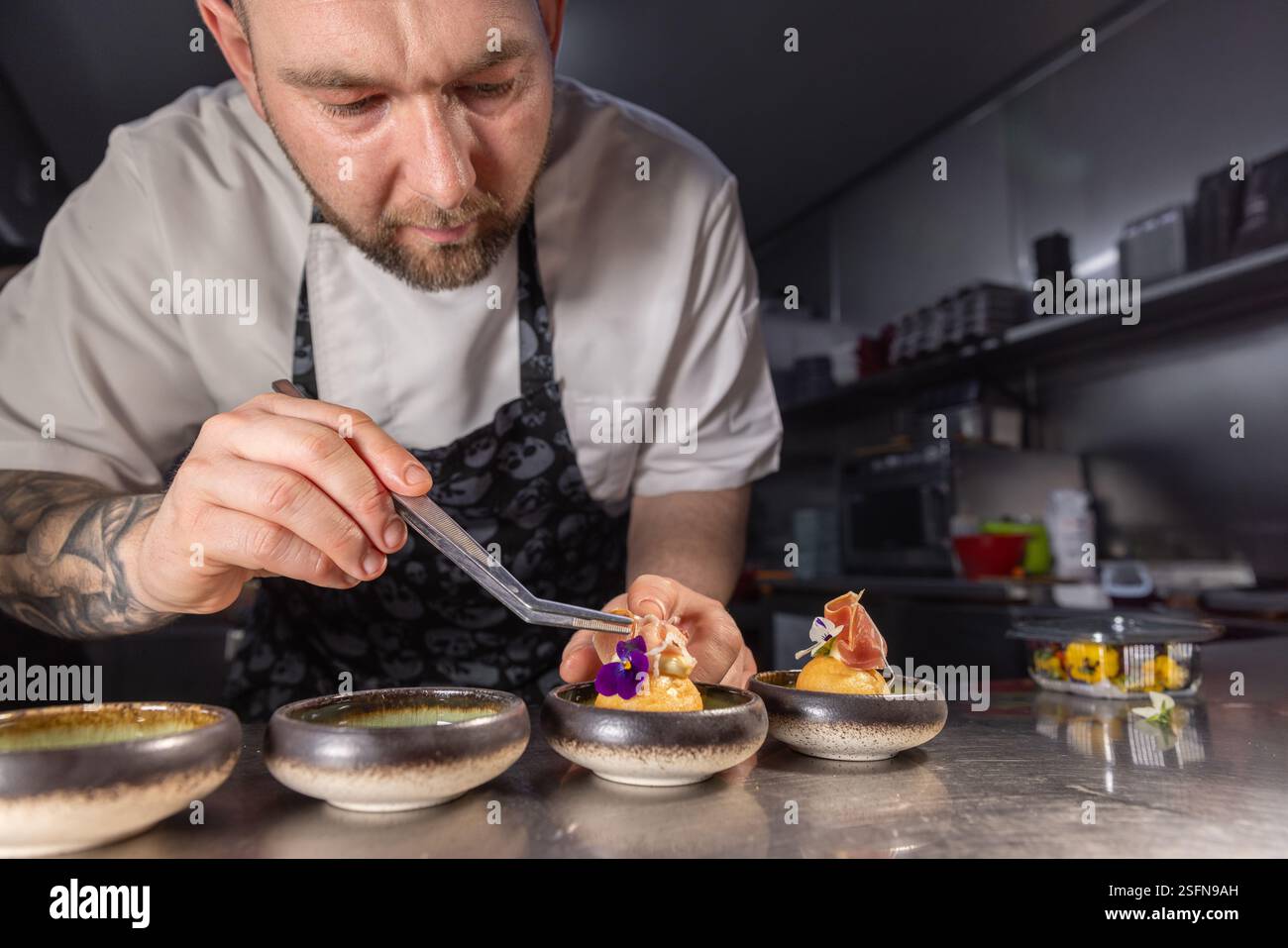 Professional chef garnishing small appetizers with prosciutto and ...