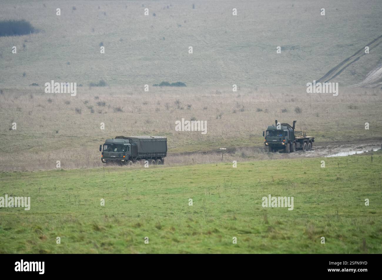 convoy of British army Heavy Utility Trucks driving along a dirt track ...