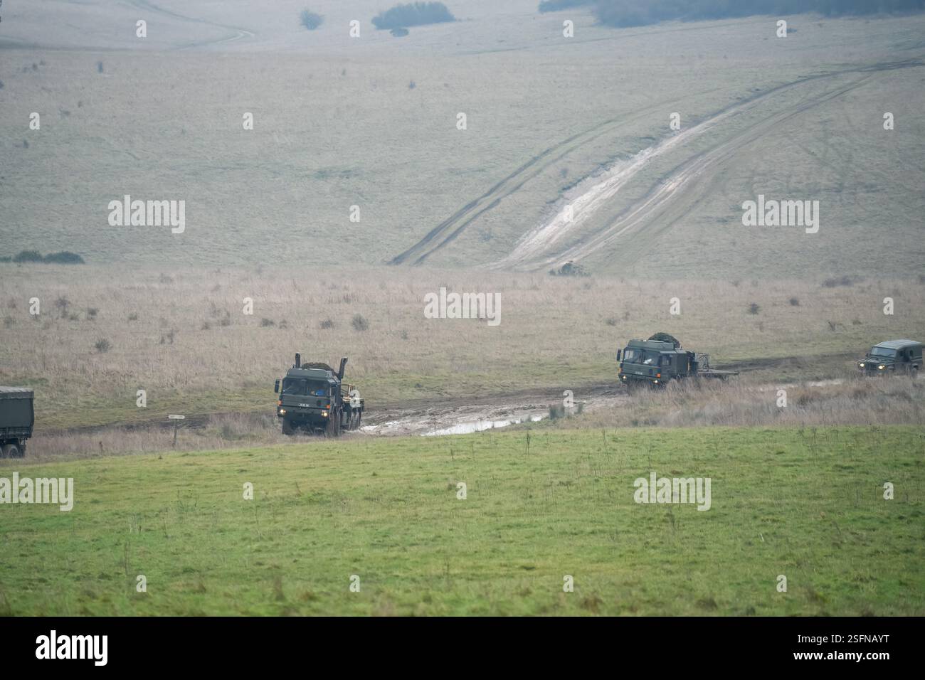 convoy of British army Heavy Utility Trucks driving along a dirt track ...