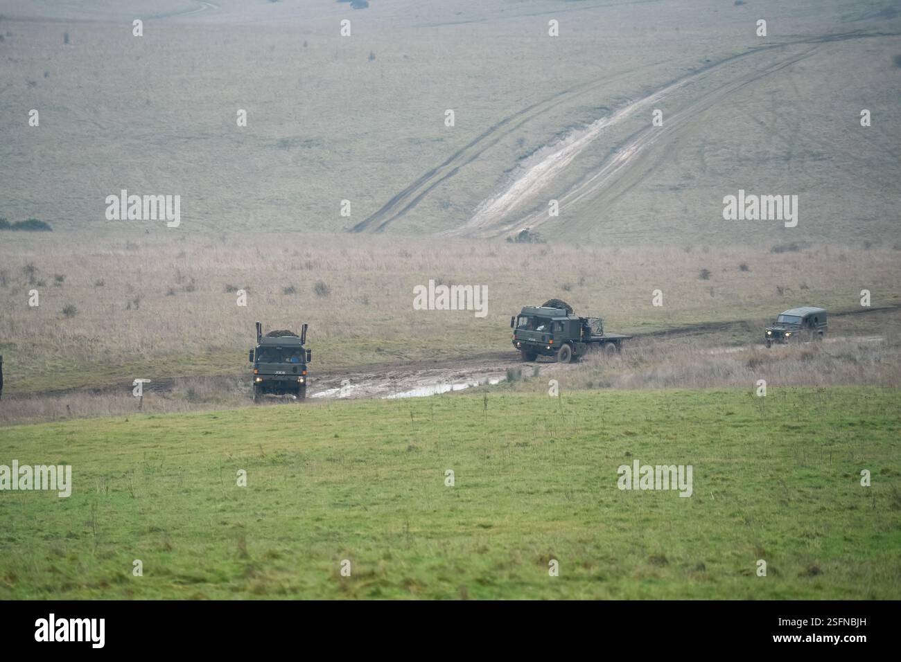 convoy of British army Heavy Utility Trucks driving along a dirt track ...